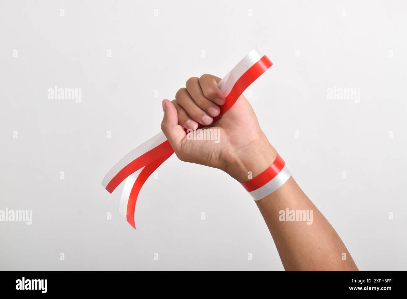 Hands clench with red and white ribbons as a symbol of the Indonesian ...