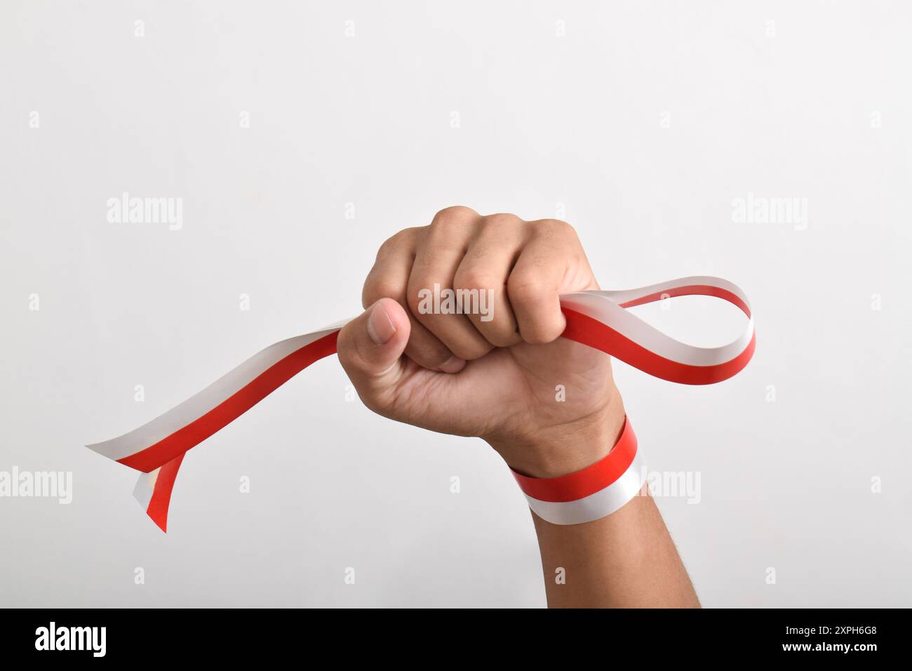 Hands clench with red and white ribbons as a symbol of the Indonesian ...
