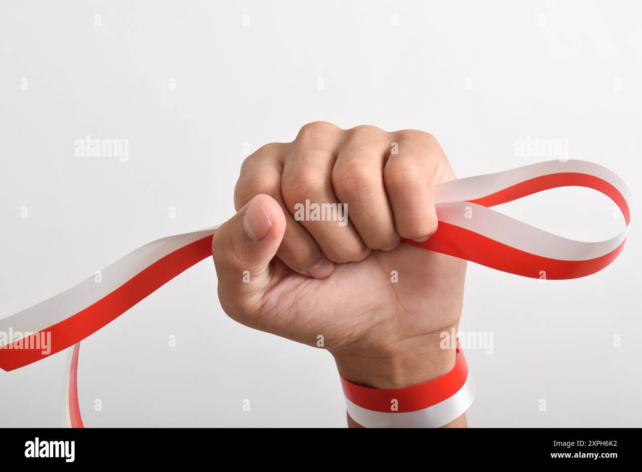 Hands clench with red and white ribbons as a symbol of the Indonesian ...