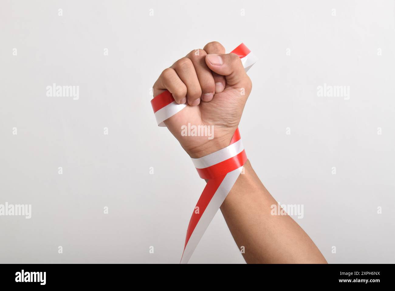 Hands clench with red and white ribbons as a symbol of the Indonesian ...