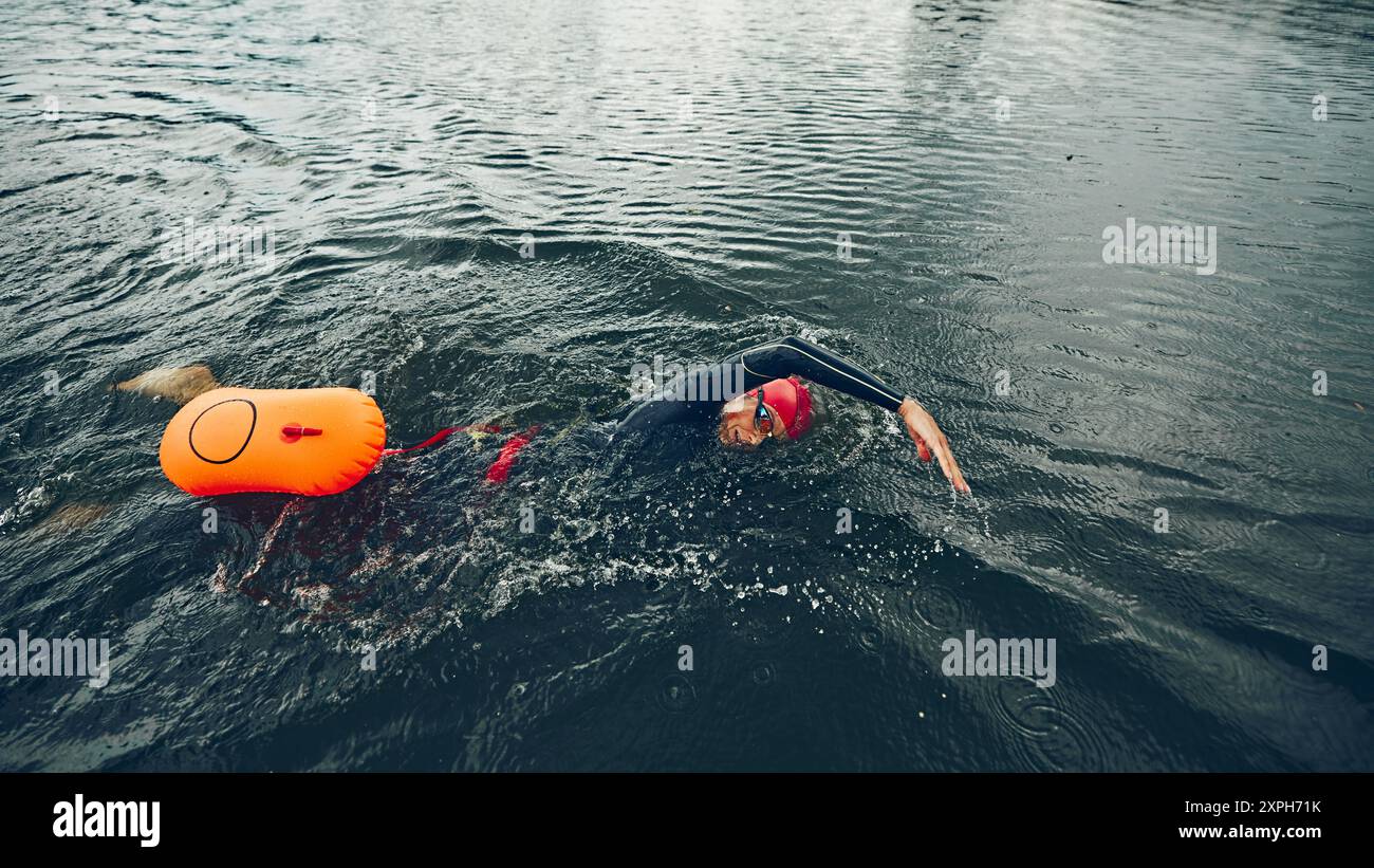 Aerial view of swimmer in black wetsuit and red cap powers through ...