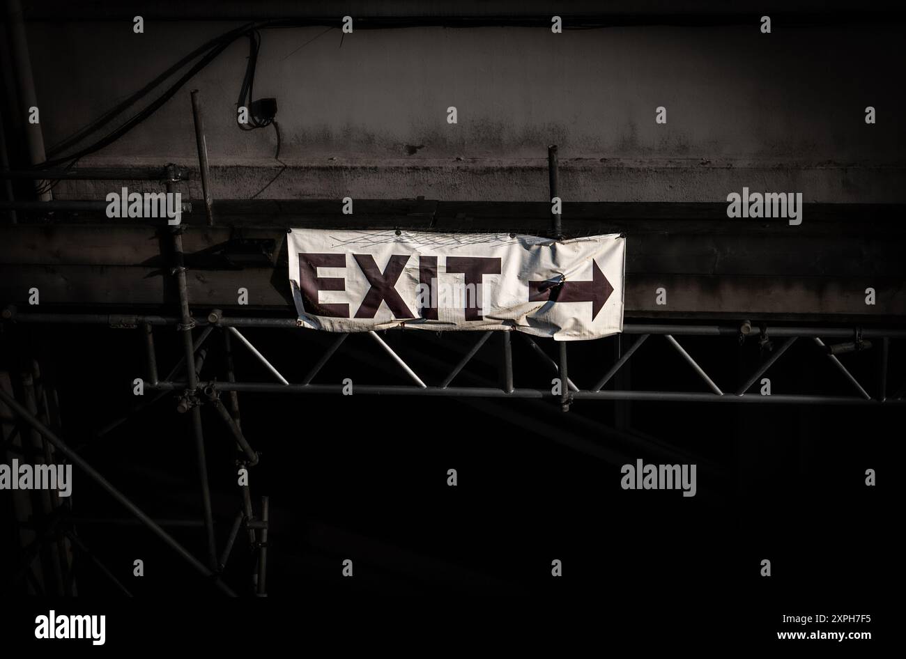 Exit sign with an arrow on a weathered white banner among a dark ...