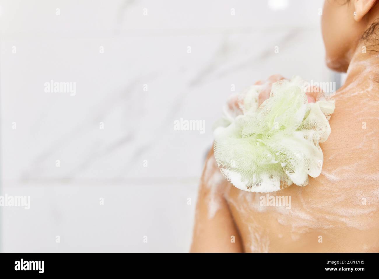 Caucasian woman washing her shoulder with sponge in white shower, copy ...