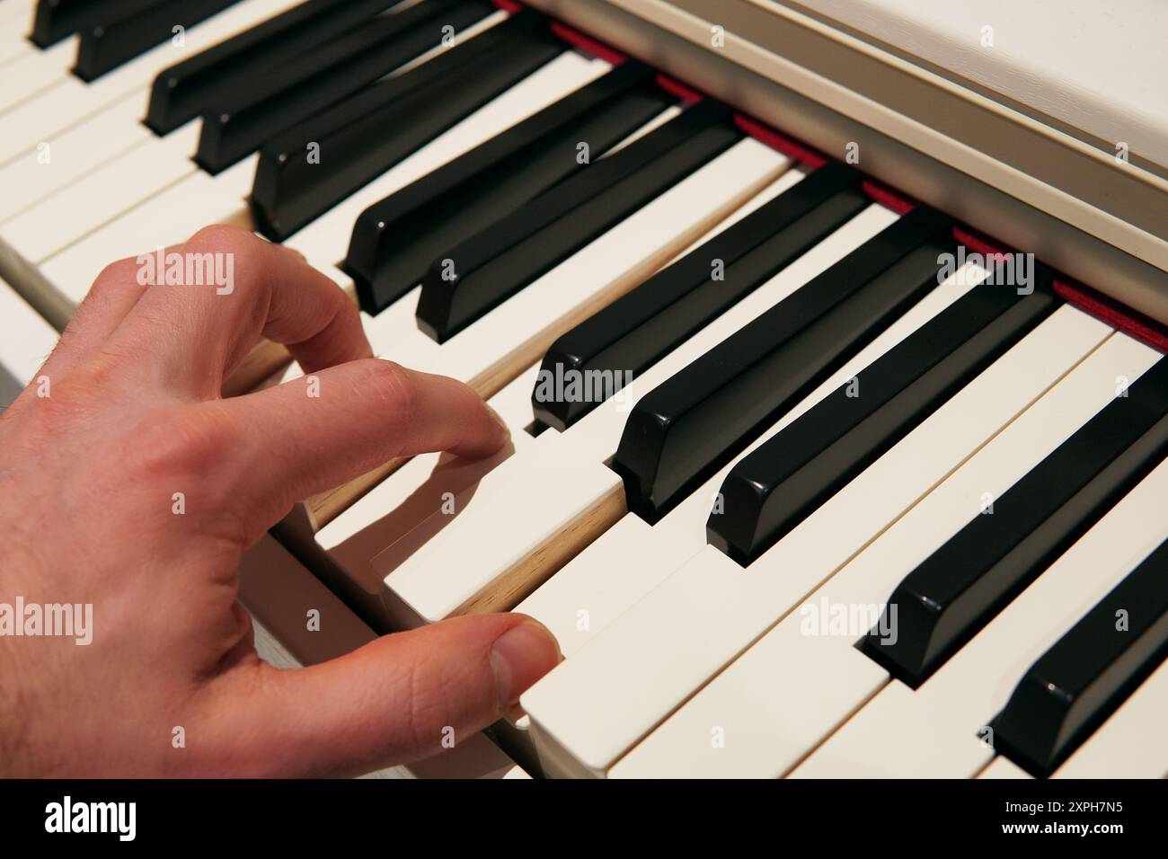 Close shot on a hand playing on the white keys of a piano Stock Photo ...