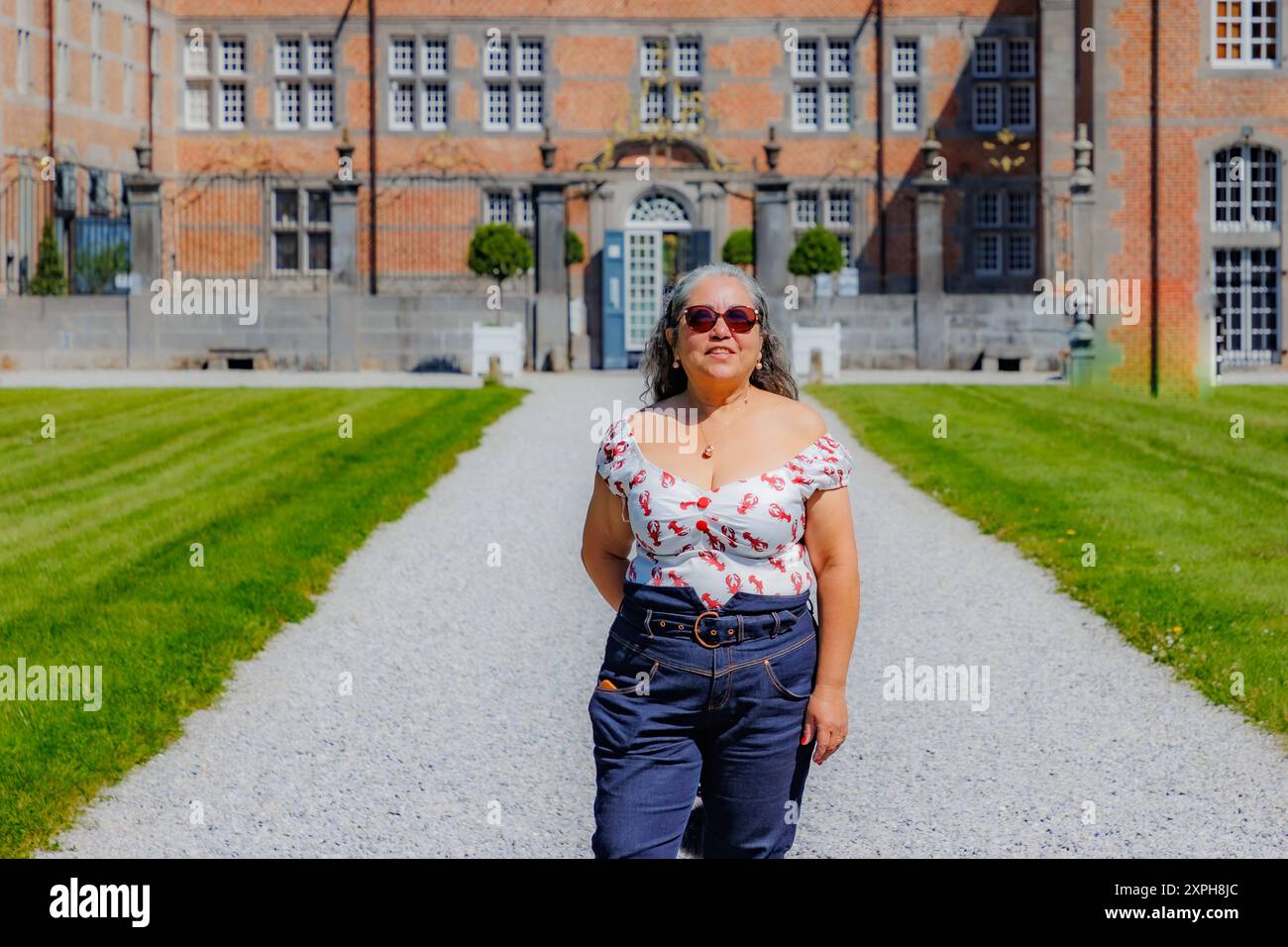 Smiling adult female tourist posing at Freyr Castle entrance on blurred ...