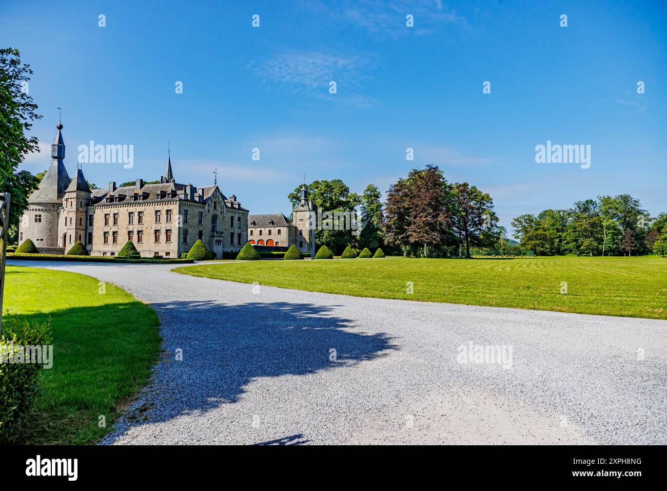 Front courtyard at entrance of Boussu-en-Fagne castle against blue sky ...