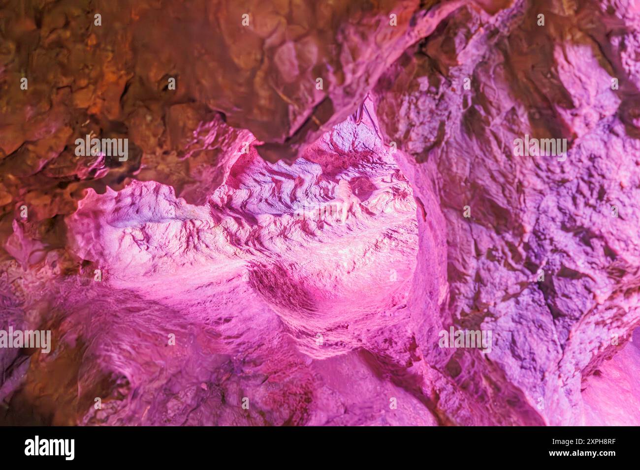 Tunnel in an underground rock formation illuminated with artificial ...