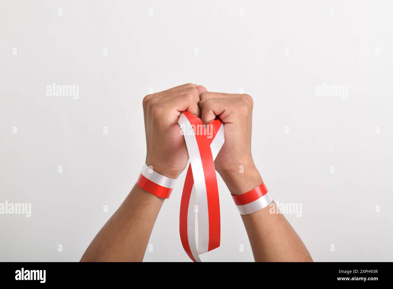 Both clenched hands holding red and white ribbon as a symbol of ...