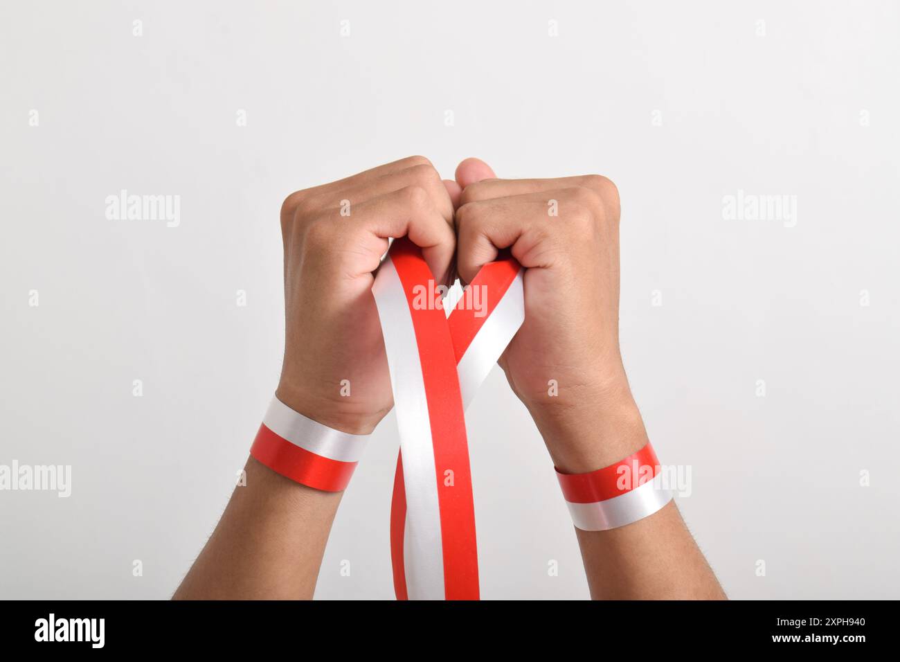 Both clenched hands holding red and white ribbon as a symbol of ...