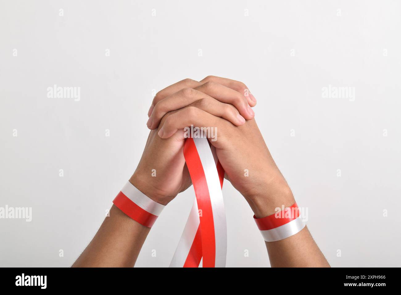 Both clenched hands holding red and white ribbon as a symbol of ...