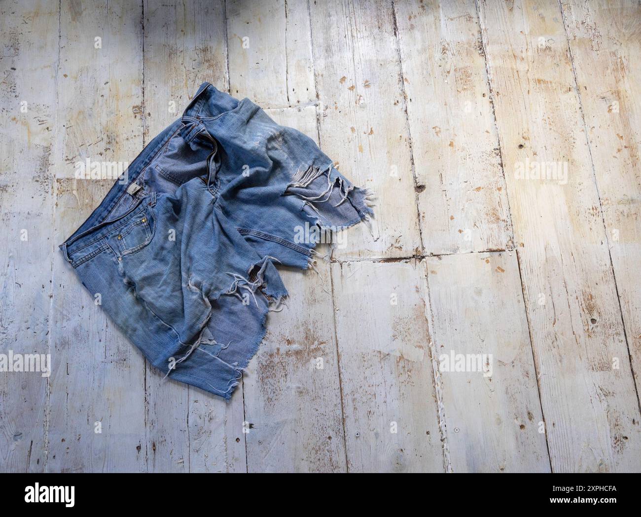 Very worn cutoff blue denim shorts laying on white washed floorboards ...