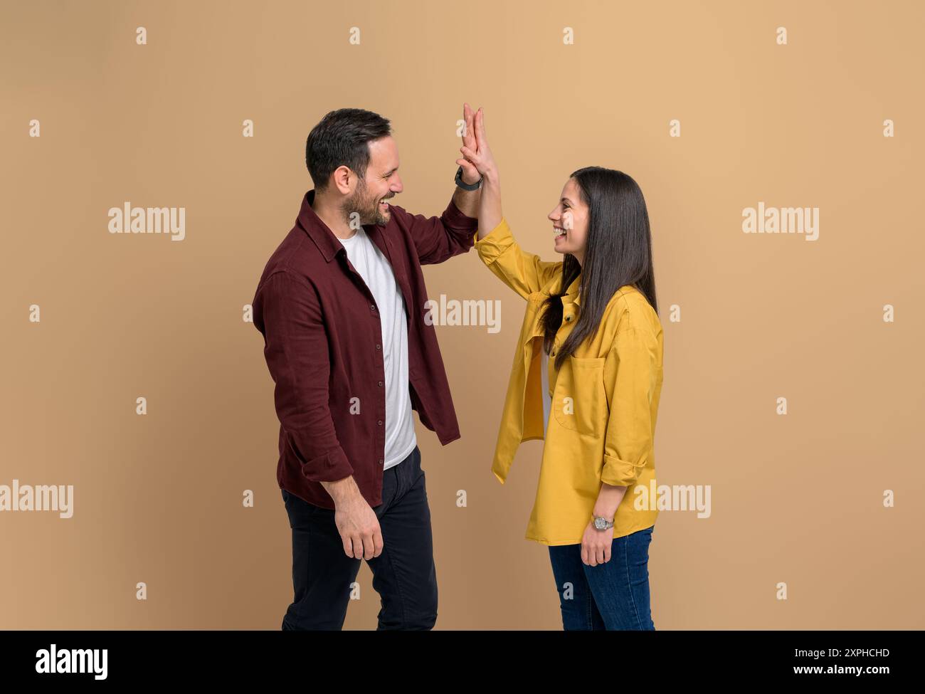 Side view of excited man and woman smiling and giving high-five to each ...
