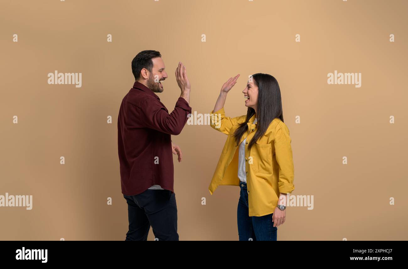 Side view of cheerful boyfriend and girlfriend giving high-five to each ...