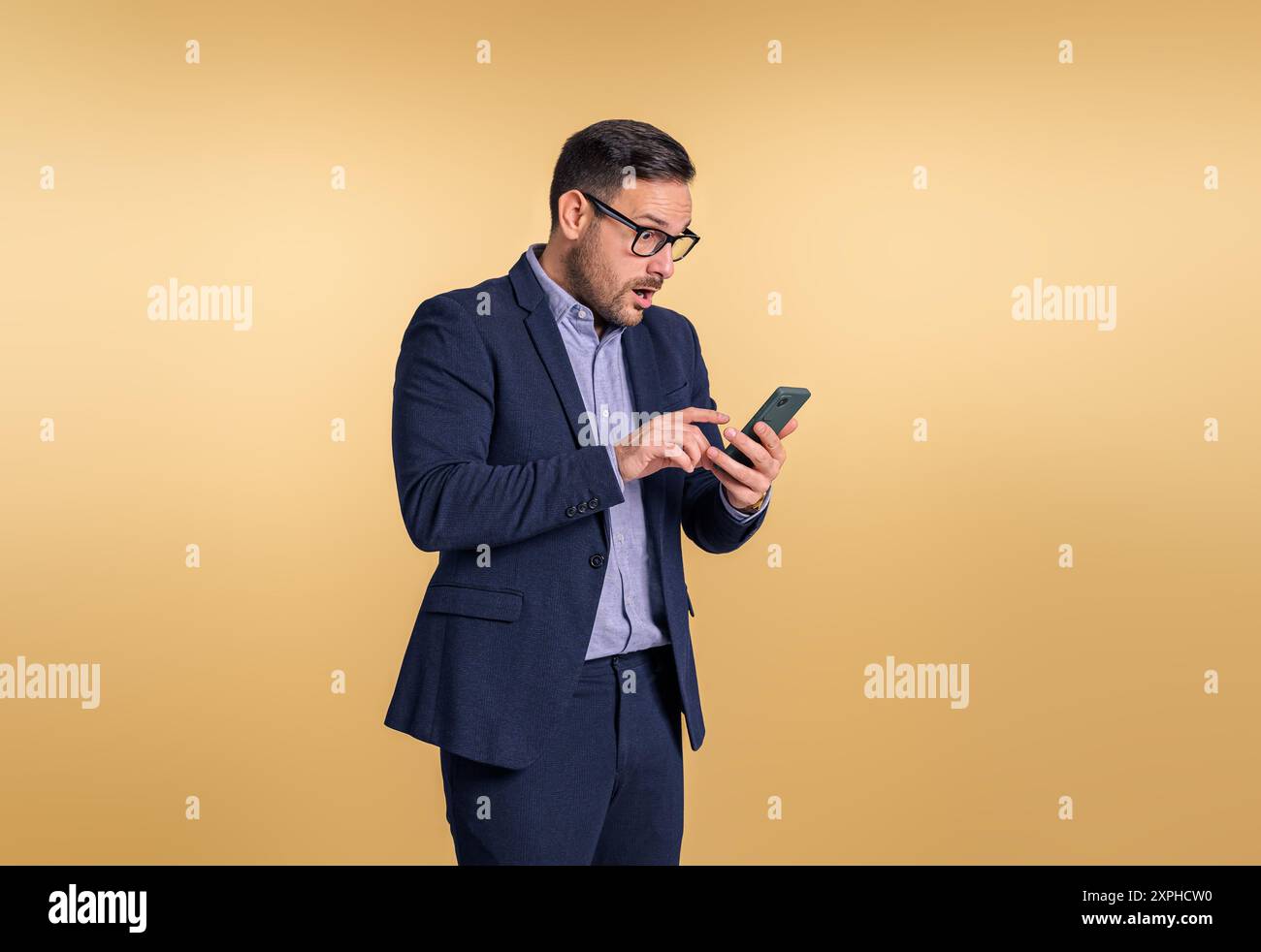 Shocked young CEO with mouth open reading bad news over mobile phone ...