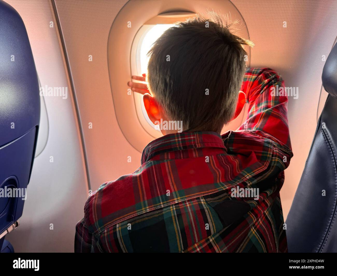 caucasian boy travelling by plane looking outside at aerial sky view ...
