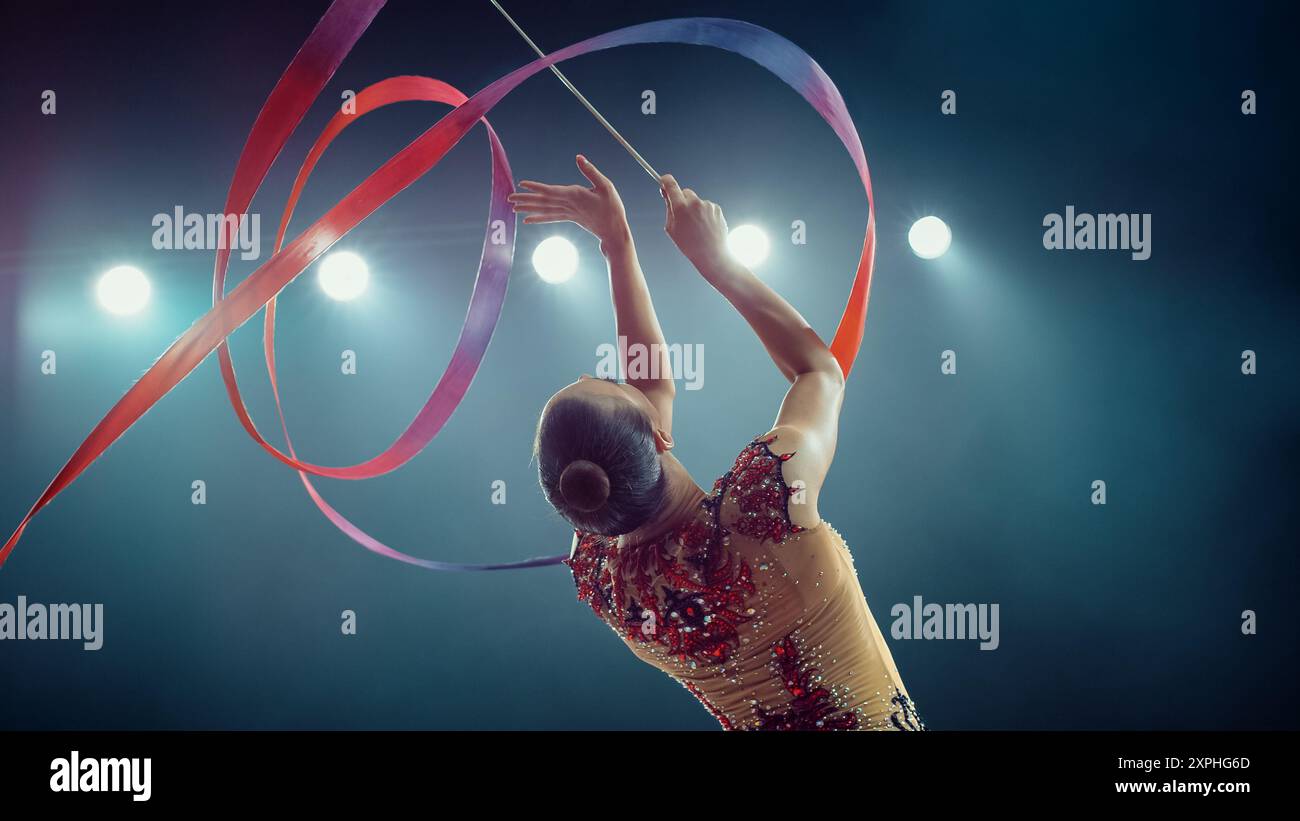 Asian Female Gymnast Elegantly Twirls Vibrant Ribbon Under Bright ...