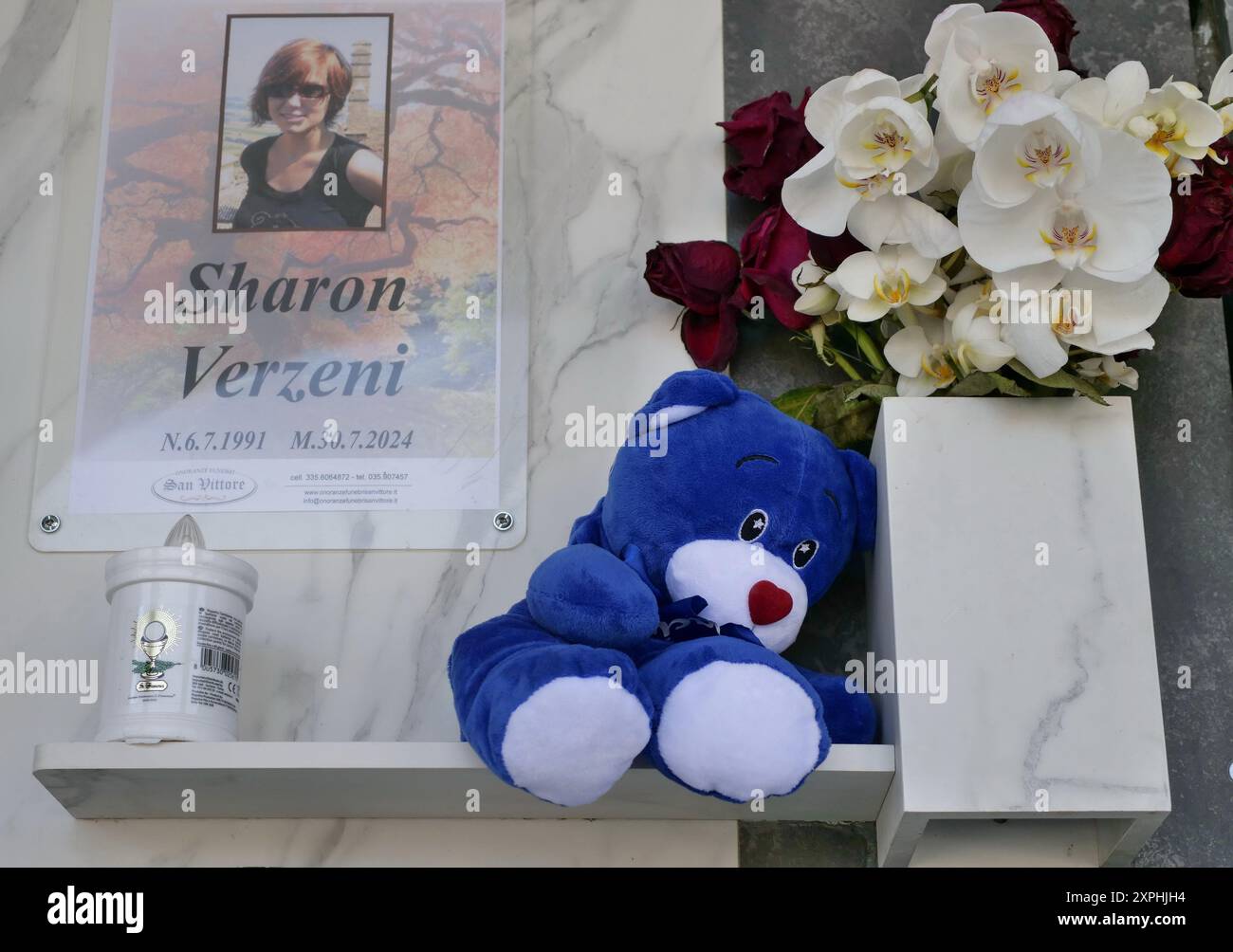 A blue teddy bear, flowers, candles and notes at the cemetery and at ...