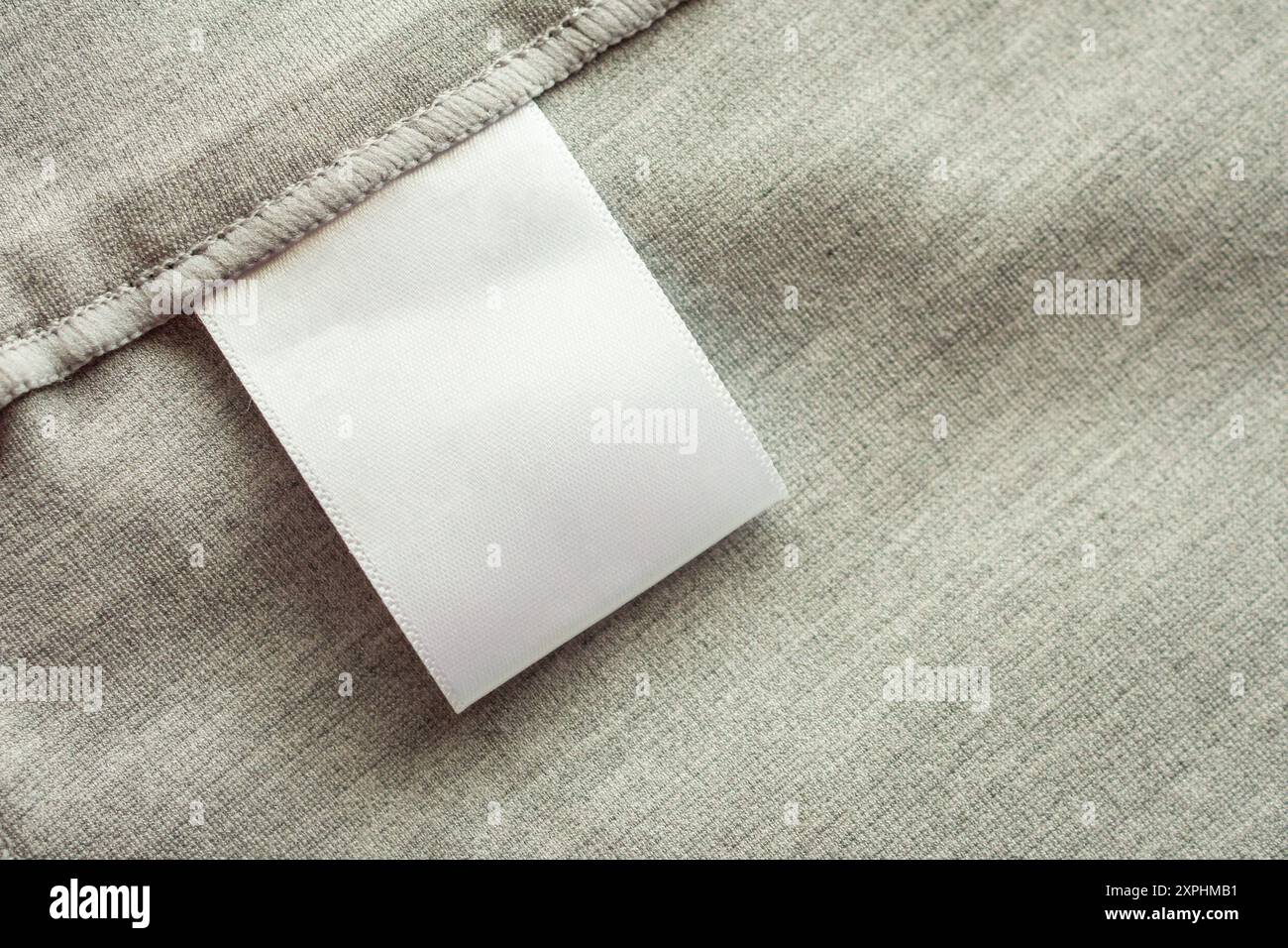 White blank laundry care clothing label on gray fabric texture ...