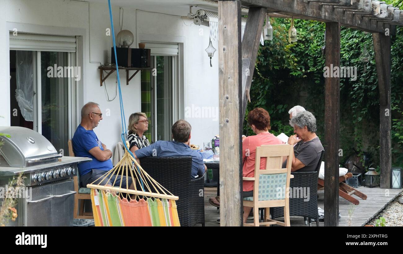 A group of people are sitting outside on a patio, enjoying a meal ...