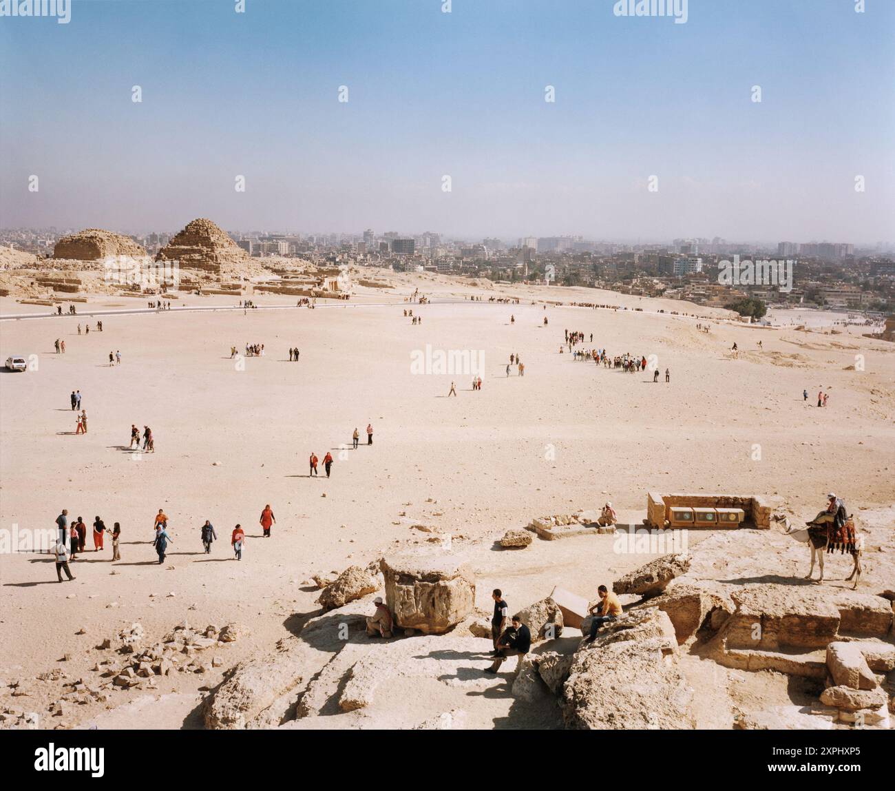A serene daytime view of the Giza Plateau features numerous visitors ...