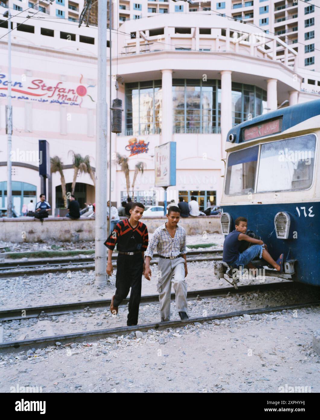 Two boys walking by a stationary train in Alexandria, Egypt, with a ...