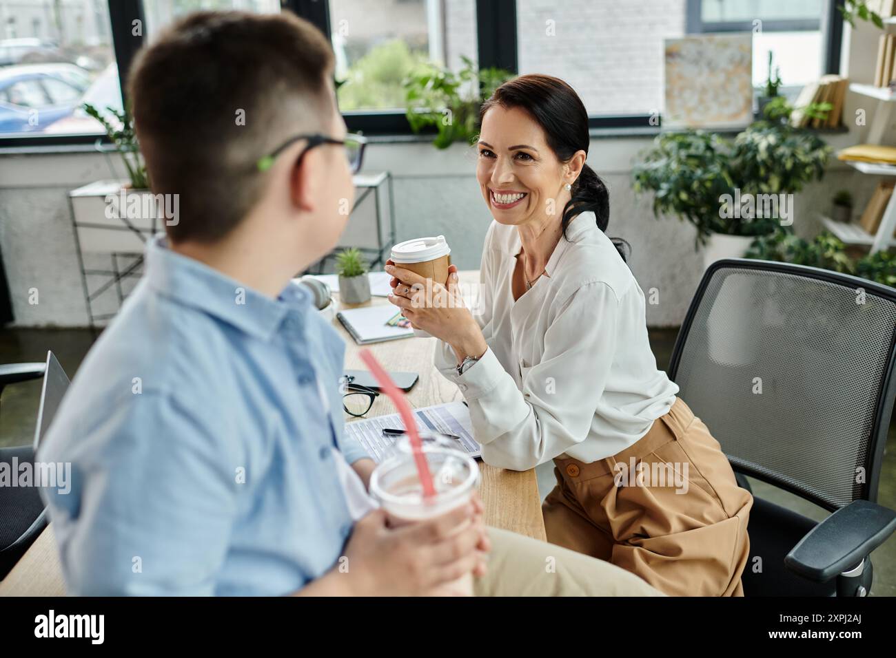 A mother smiles at her son while they share a coffee break in the ...