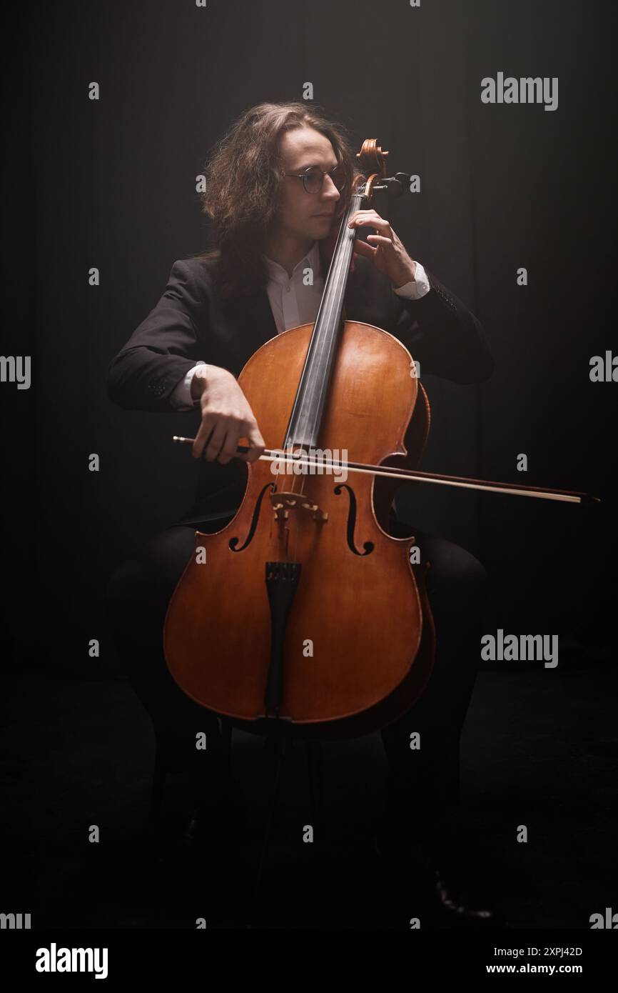Vertical full shot of professional male musician playing cello solo ...