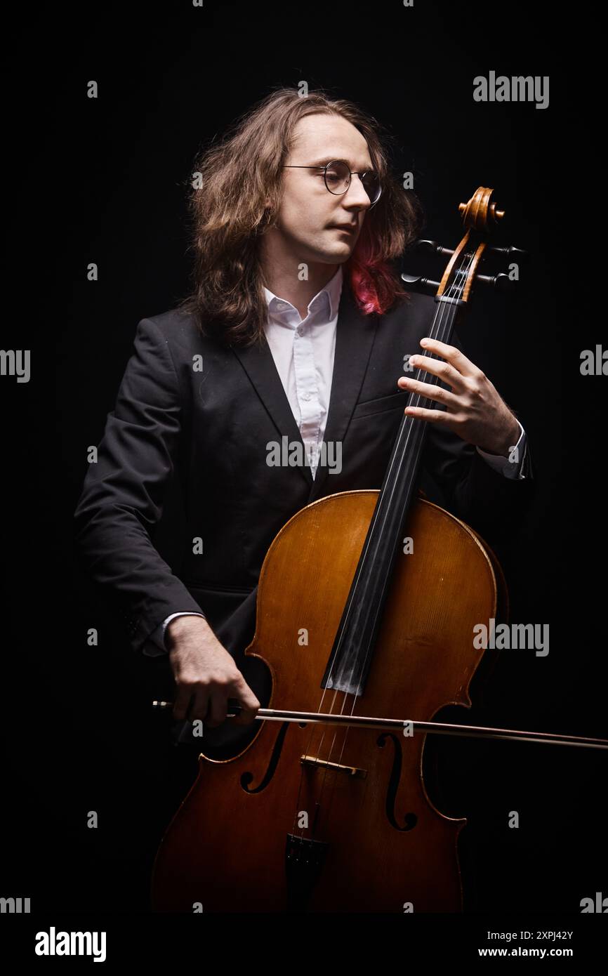 Vertical medium full shot of professional male musician in black suit ...