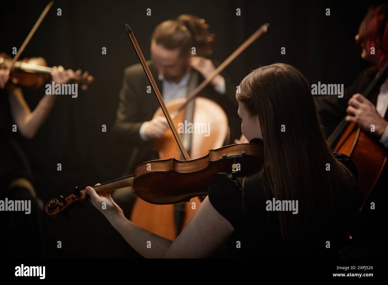 Rear view of unrecognizable female violin player in shadow performing ...