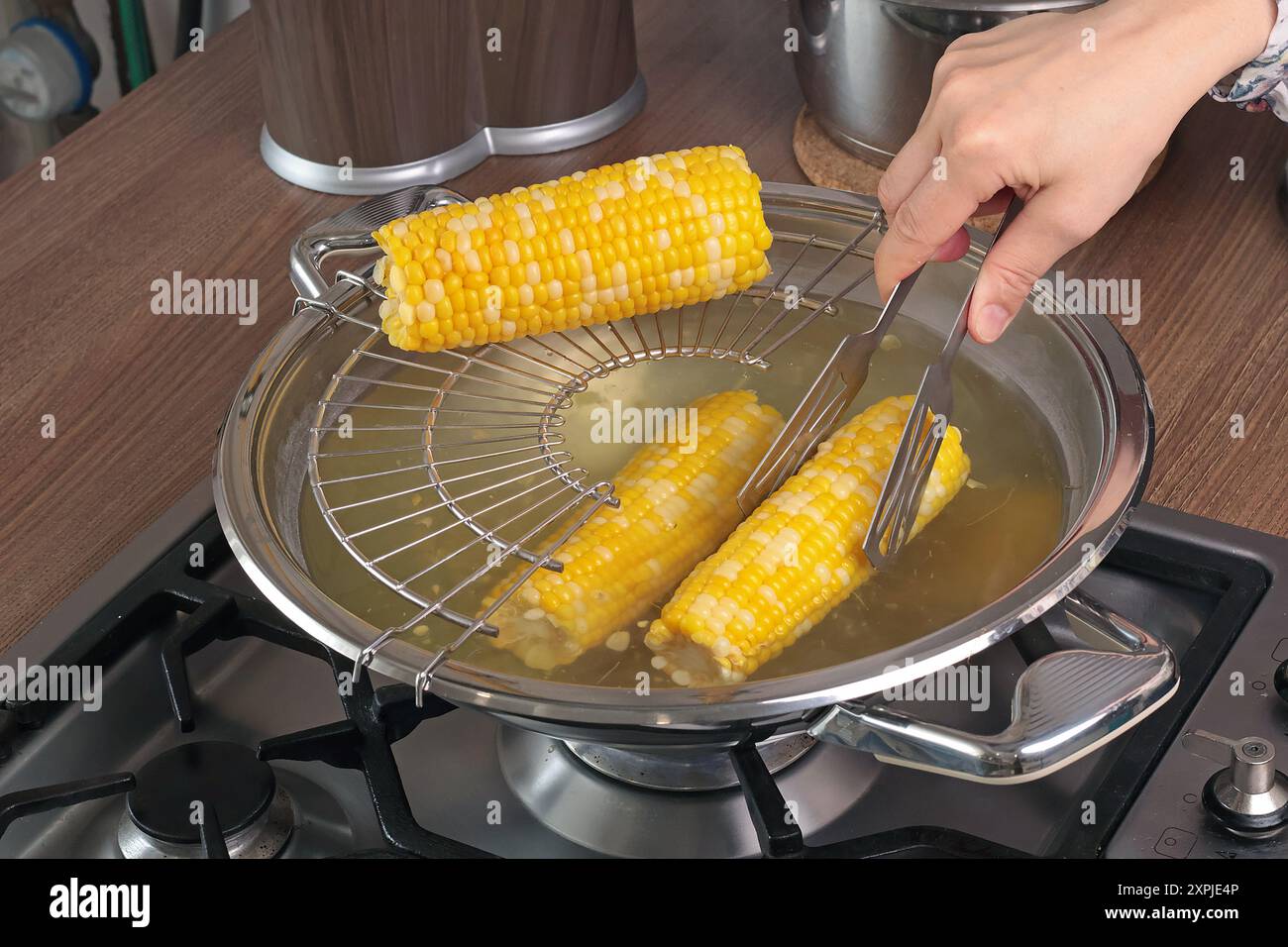 Anonymous woman cook corn in wok and lay on pot lattice rack. Food and ...
