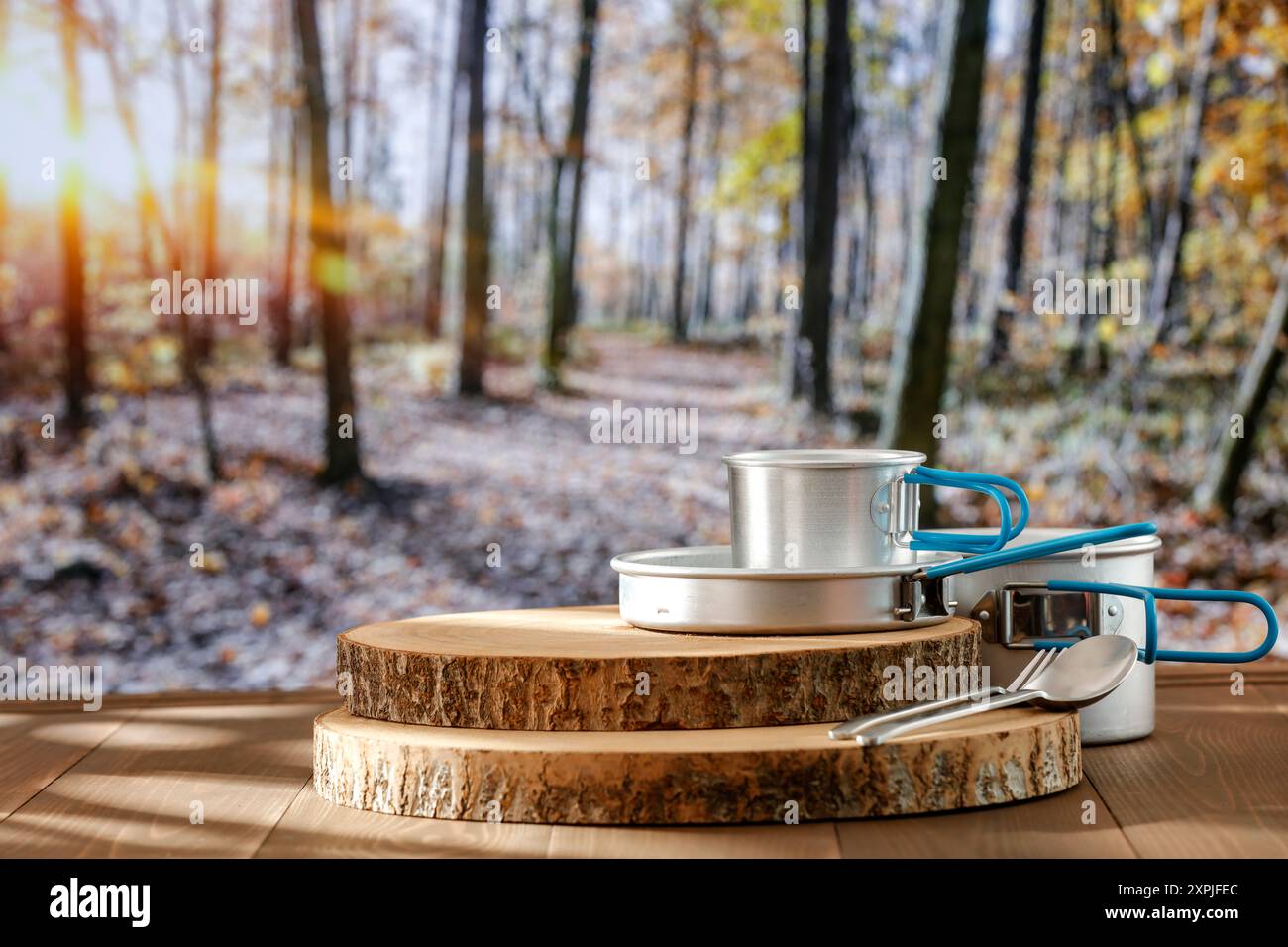 Aluminium dishes and mess tin on wooden autumn table and autumn trees ...