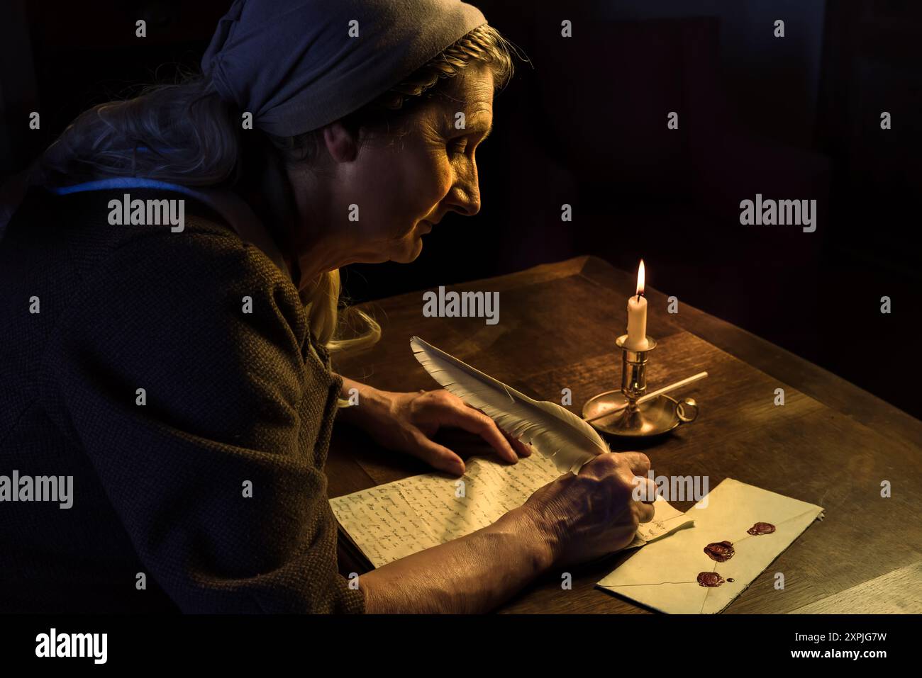 woman in medieval peasant costume writing a letter with a feather quill ...