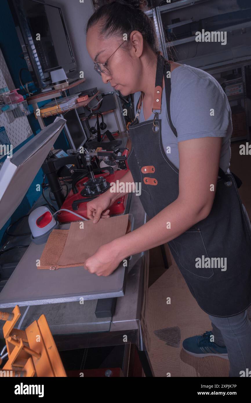 Young working woman in her workshop makes the sublimation process with ...