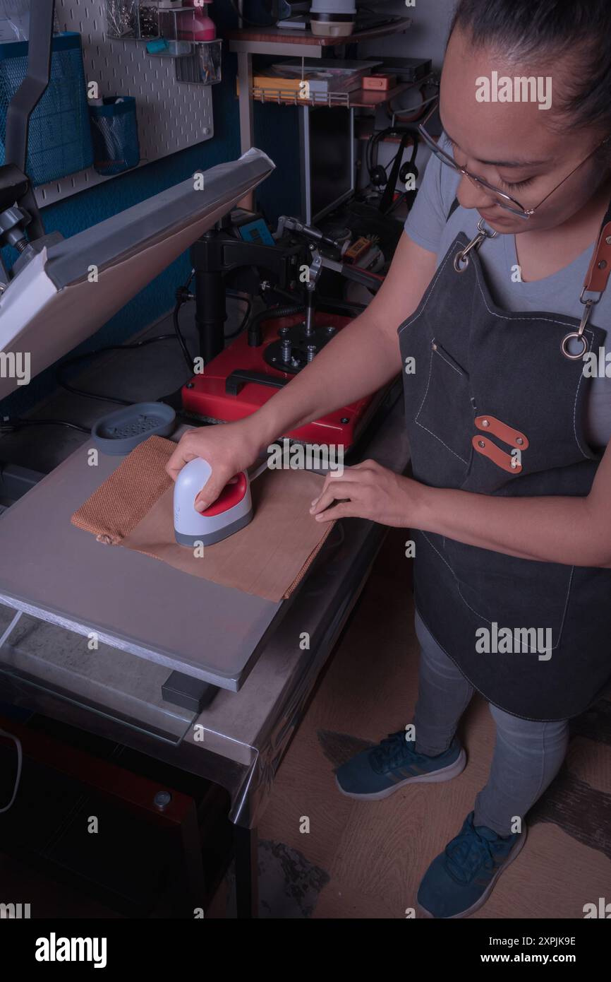 Young working woman in her workshop makes the sublimation process with ...