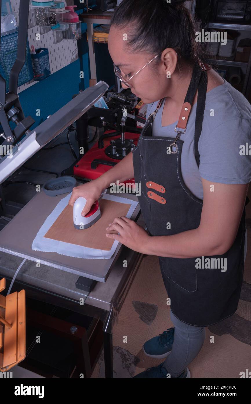 Young working woman in her workshop makes the sublimation process with ...