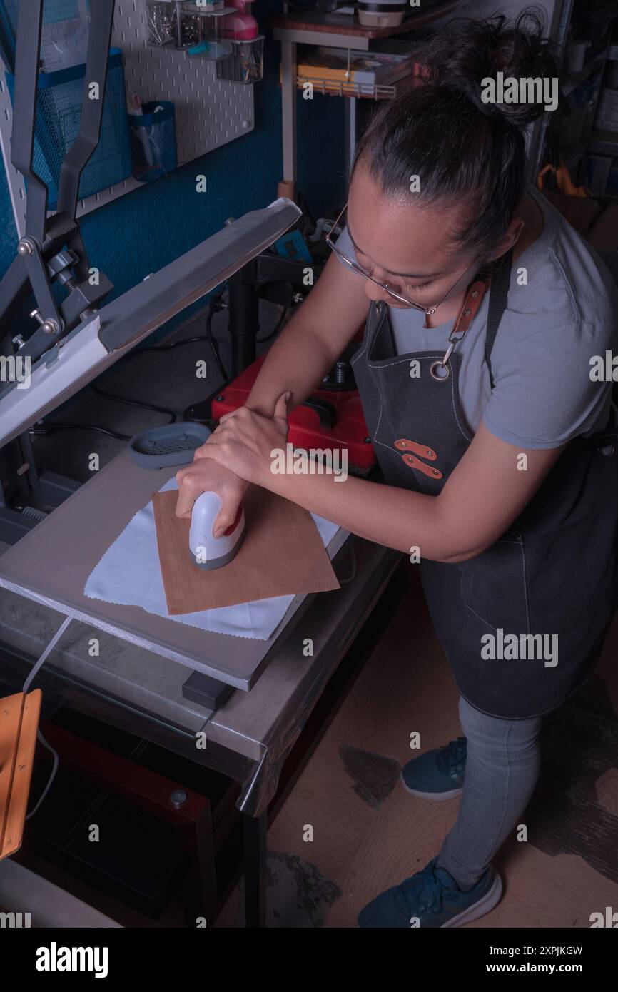 Young working woman in her workshop makes the sublimation process with ...