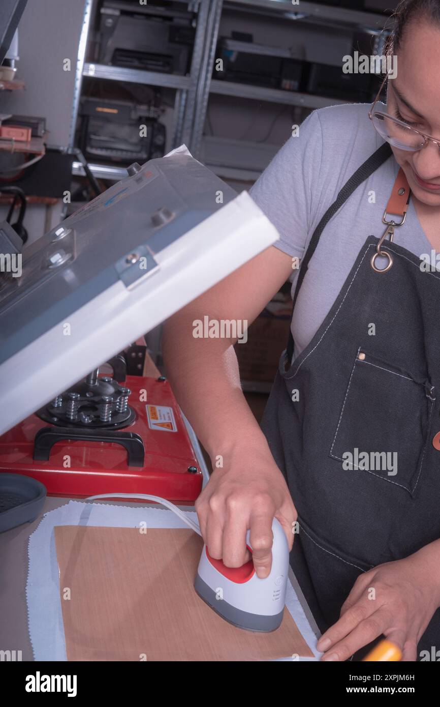 Young working woman in her workshop makes the sublimation process with ...