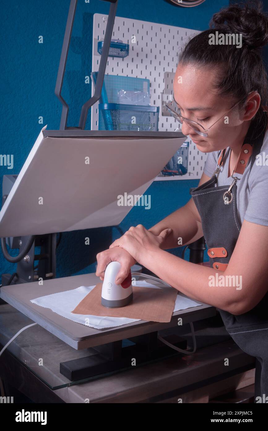 Young working woman in her workshop makes the sublimation process with ...
