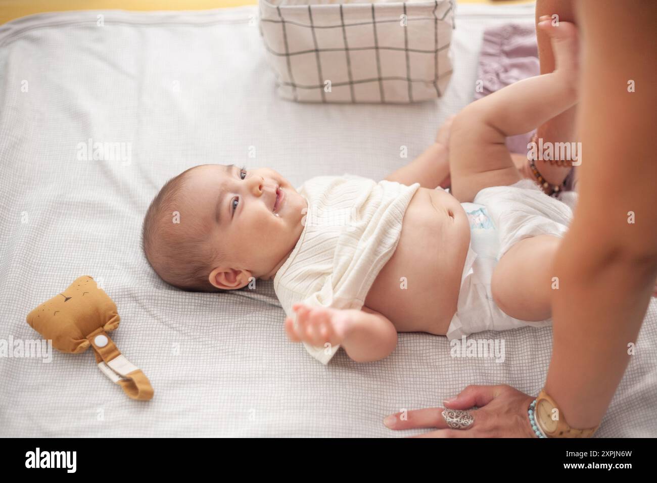 Baby on top of a blanket where his mother changes his diaper. The baby ...