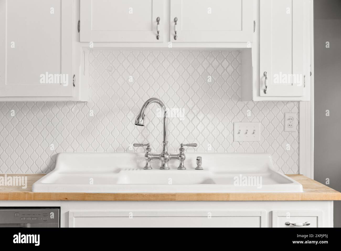 A kitchen faucet detail with a large white farmhouse sink with double ...