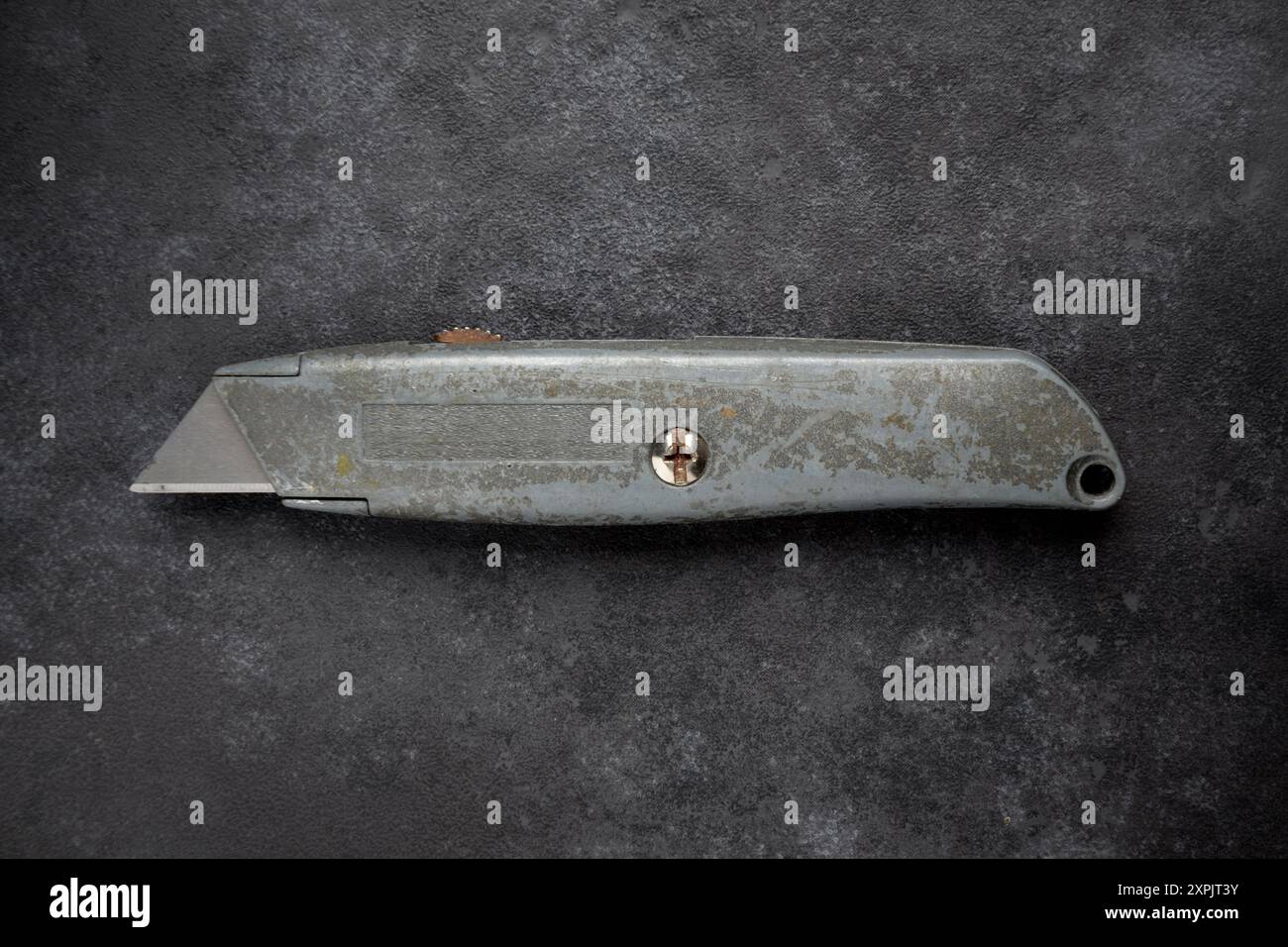 Old used metal utility knife from above on dark background with copy ...