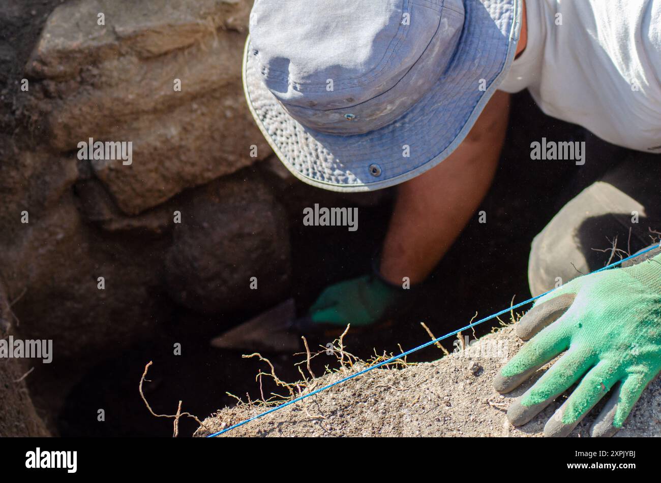 an unrecognizable archaeologist digging with a trowel, concept ...