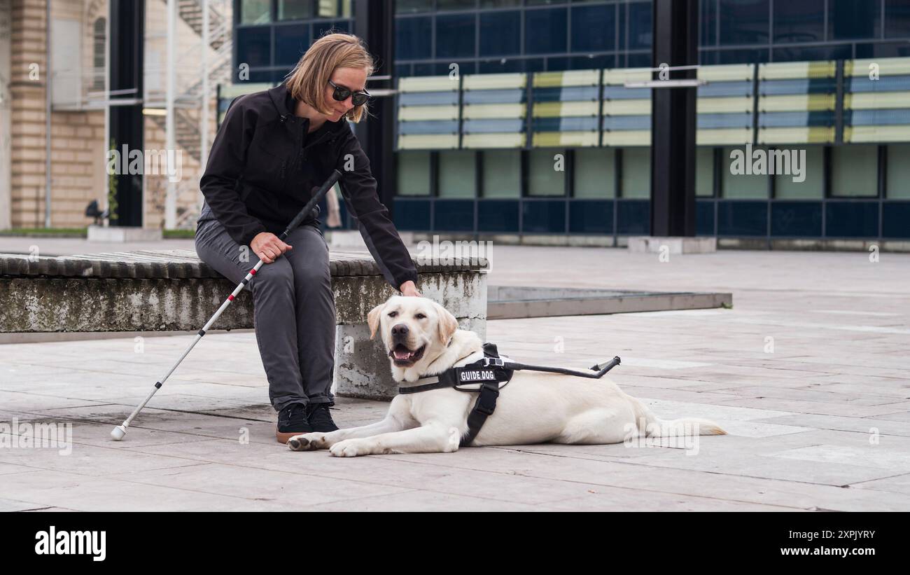 Blind or visually impaired woman resting with her guide dog on the ...