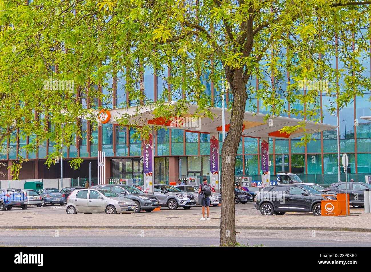 Drivers filling up their cars at a gas station in the city, surrounded ...