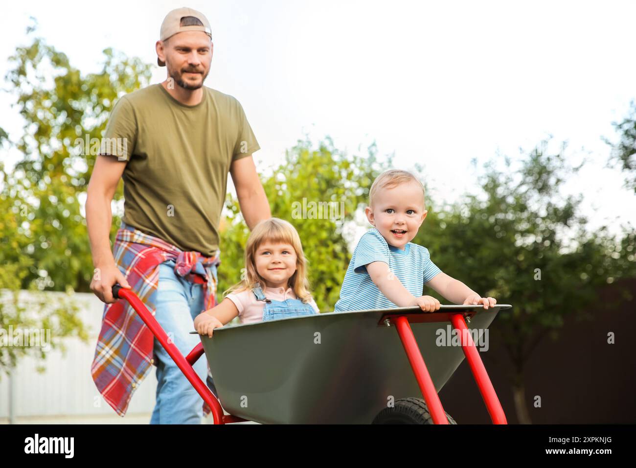 Father pushing wheelbarrow with his kids outdoors Stock Photo - Alamy