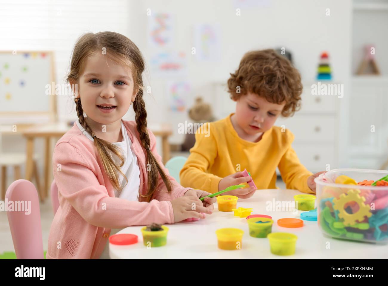 Cute little children modeling from plasticine at white table in ...