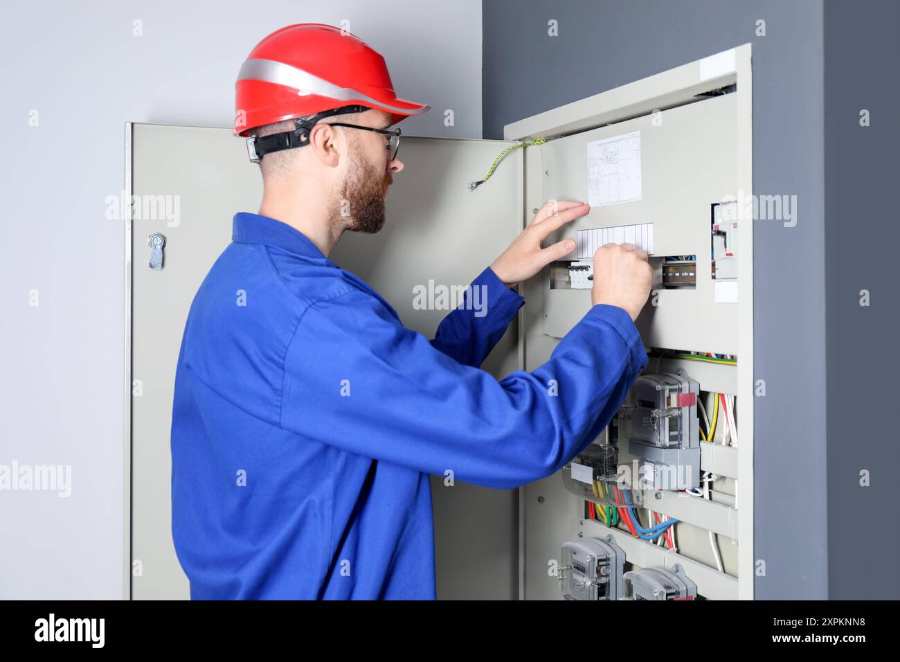 Electrician wearing uniform installing electricity meter indoors Stock ...