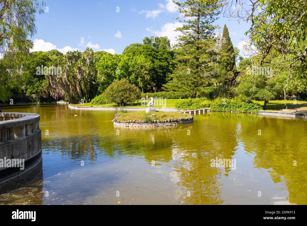 Statue standing on a small island in a pond reflecting the surrounding ...