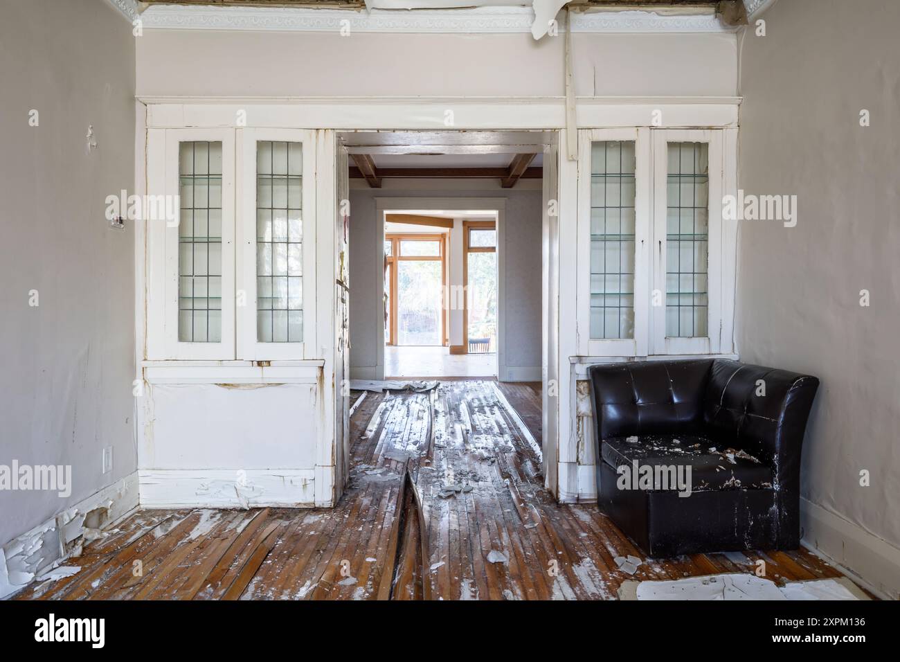 A doorway leading into another room with a chaise and a water damaged ...