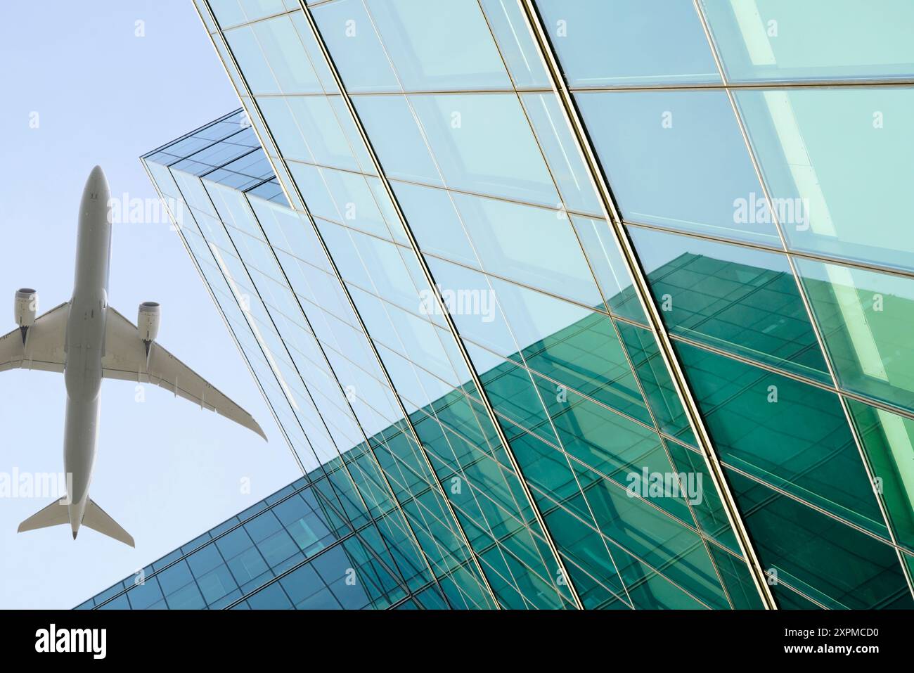 Airplane flying above modern sustainable glass office building ...